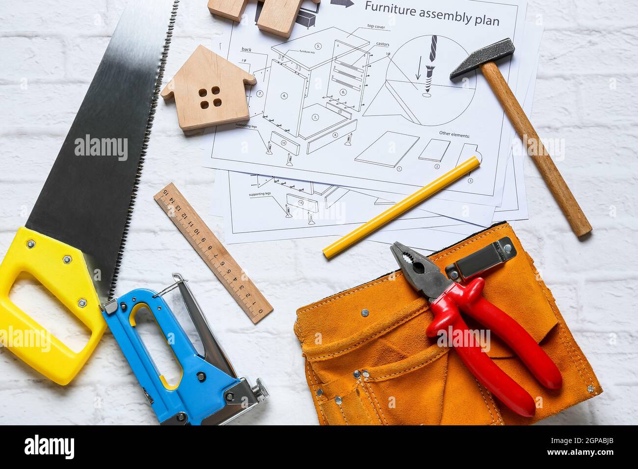 Furniture assembling plan and different tools on white brick background ...