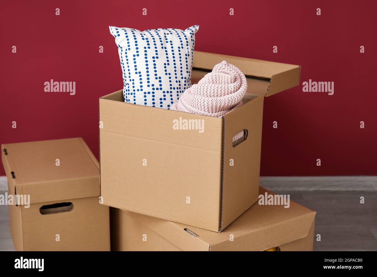 Wardrobe boxes with pillow and plaid on wooden floor near color wall ...