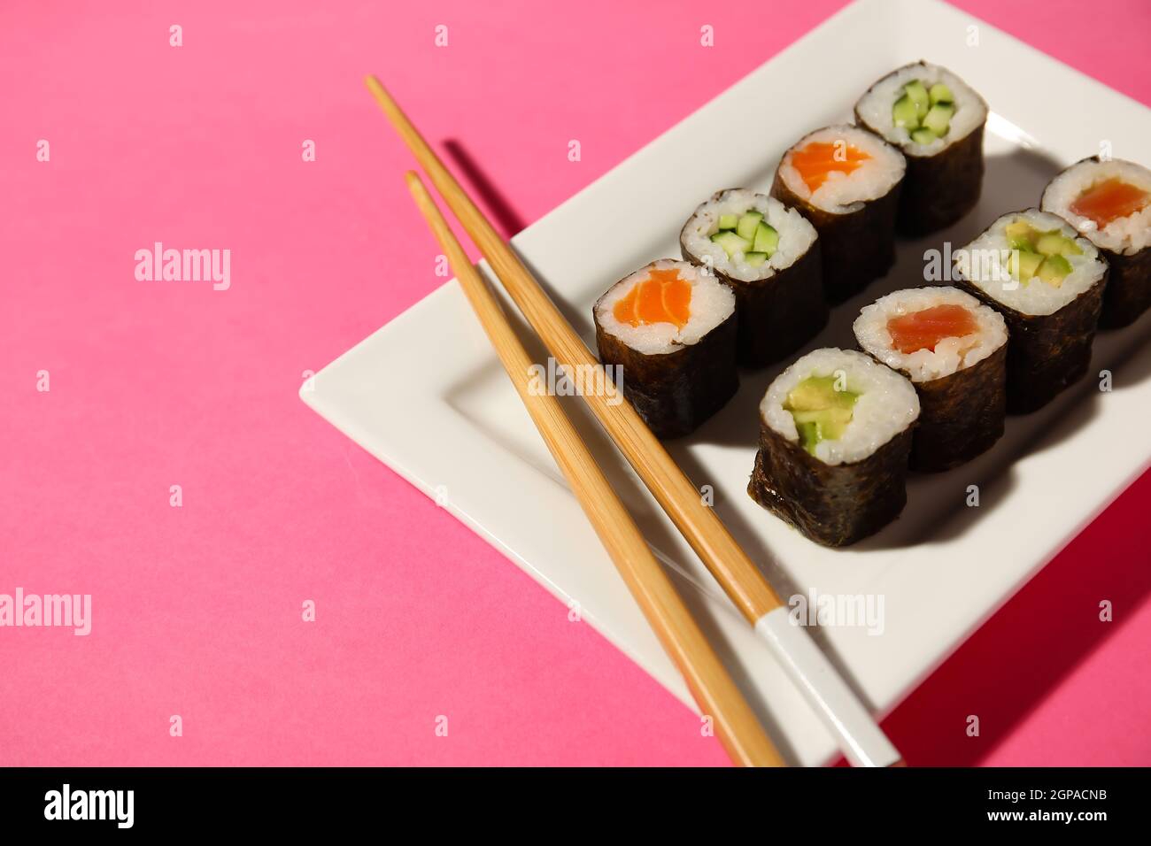 Plate with different maki rolls and wooden chopsticks on color ...