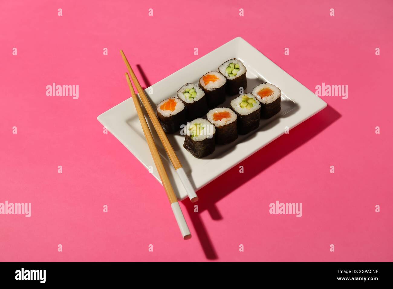 Plate with different maki rolls and wooden chopsticks on color ...