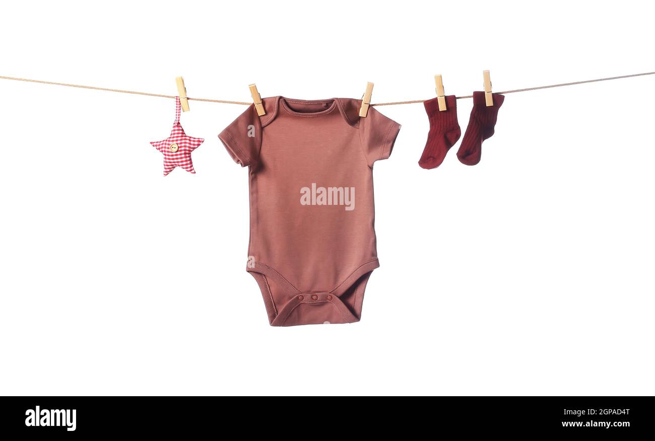Baby clothes, socks and toy hanging on rope against white background ...