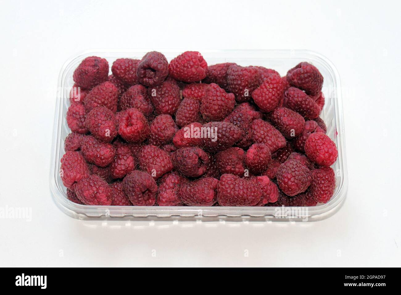 Fresh organic raw raspberries fruit pile in plastic container isolated ...