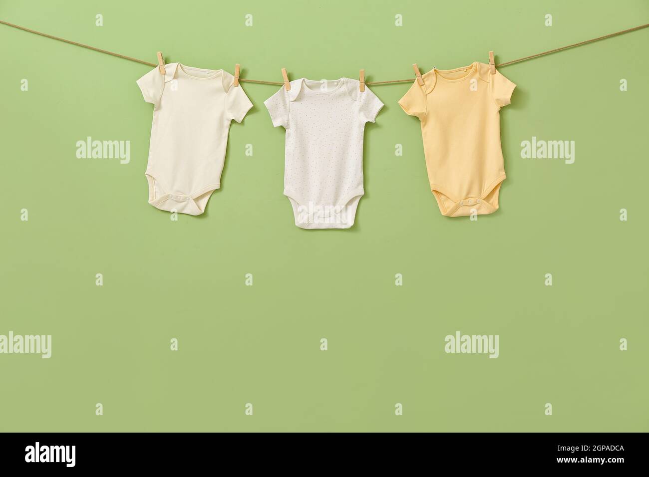 Different baby clothes hanging on rope against green background Stock ...