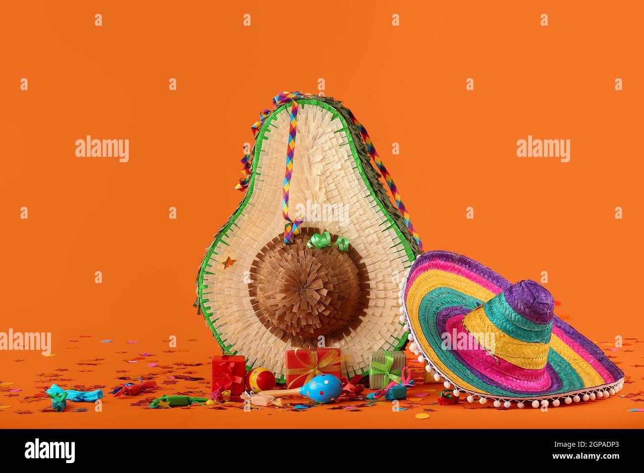 Mexican pinata with sombrero hat, maracas and gifts on color background ...
