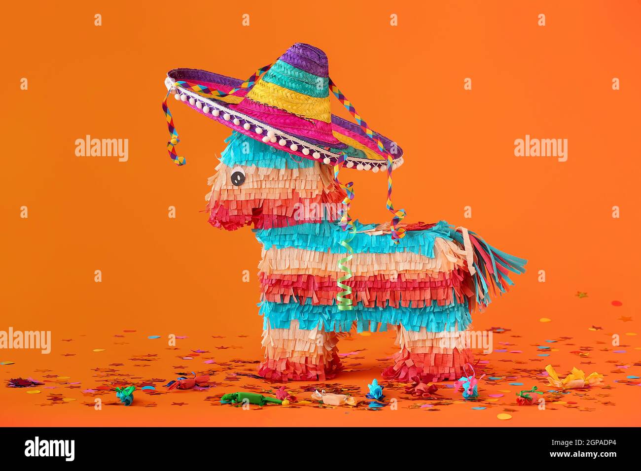 Mexican pinata with sombrero hat and confetti on orange background ...