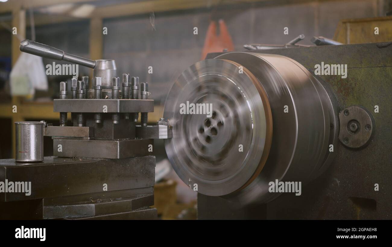 Professional machinist operating lathe grinding metal machine ...