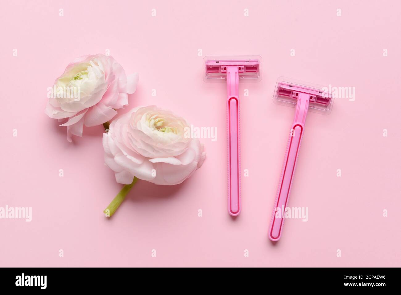 Safety razors and flowers on pink background Stock Photo - Alamy