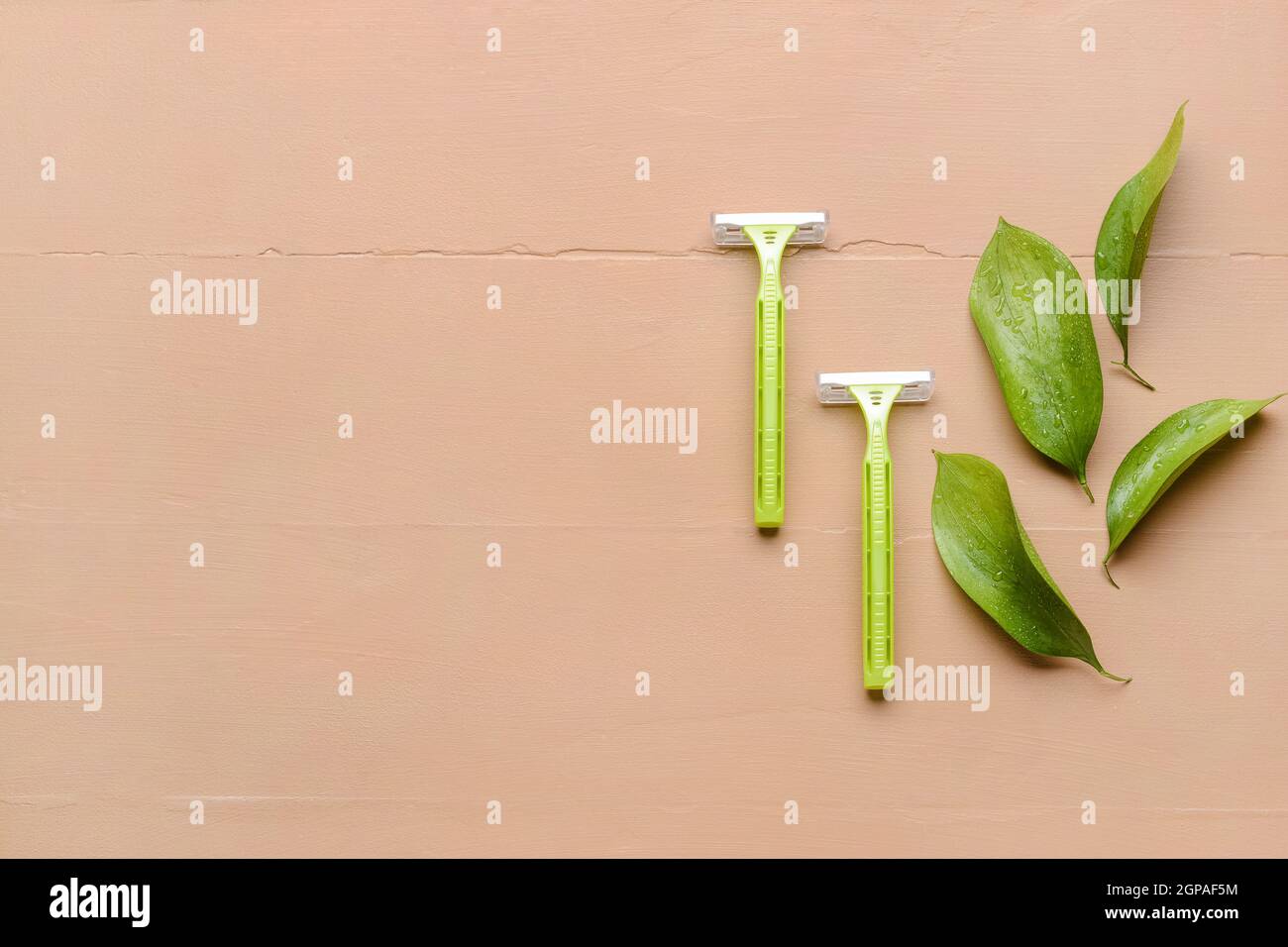 Safety razors and green leaves on color wooden background Stock Photo ...