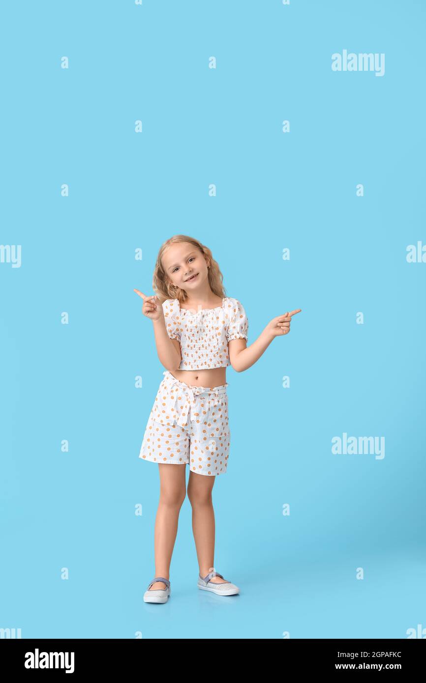 Cute little girl pointing at something on color background Stock Photo ...