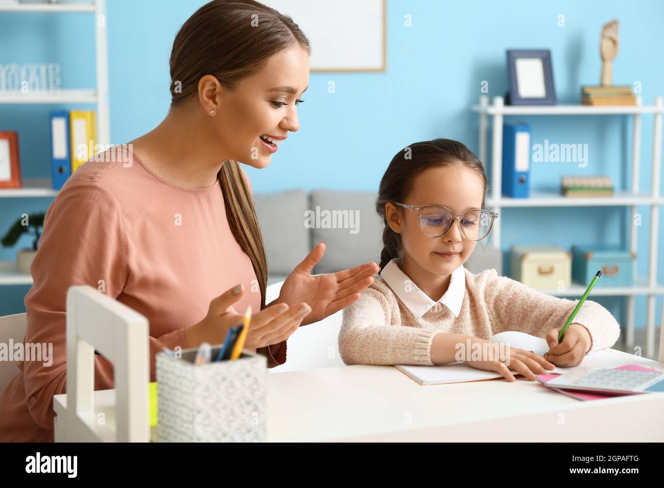Little girl with her mother doing lessons at home Stock Photo - Alamy
