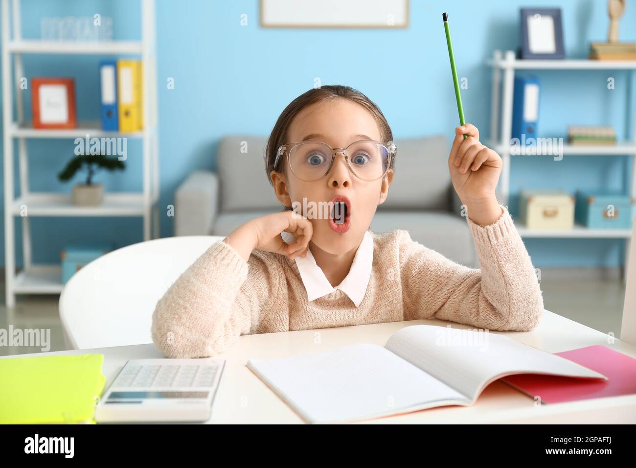 Shocked little girl doing lessons at home Stock Photo - Alamy