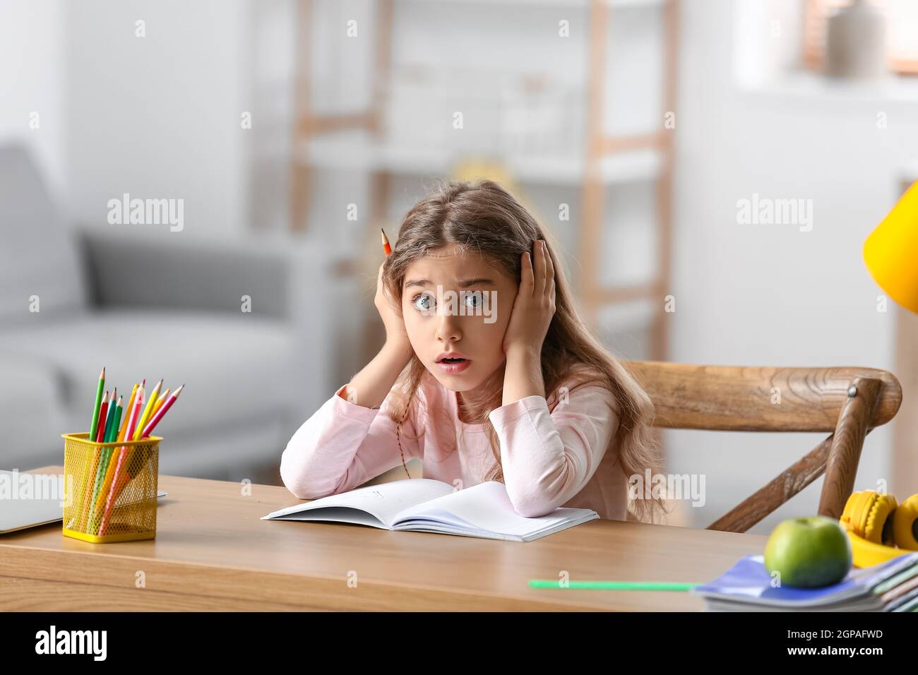 Shocked little girl doing lessons at home Stock Photo - Alamy