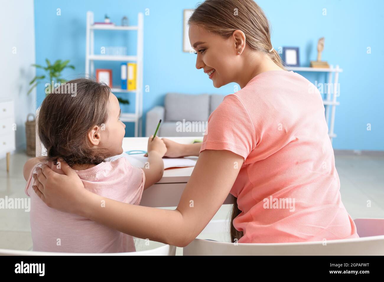 Little girl with her mother doing lessons at home Stock Photo - Alamy