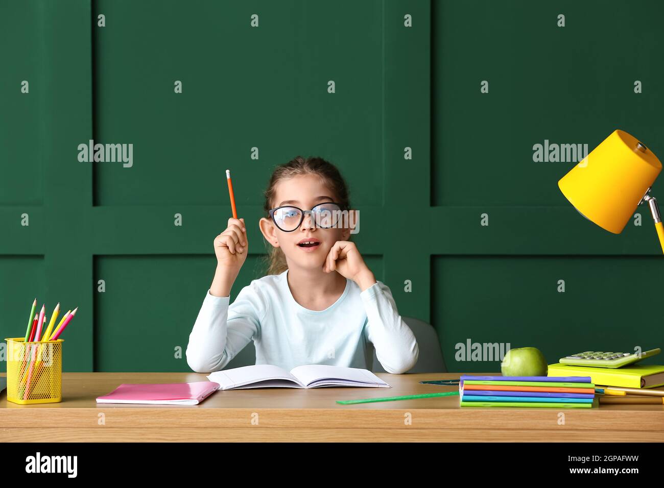 Little girl doing homework at table on color background Stock Photo - Alamy