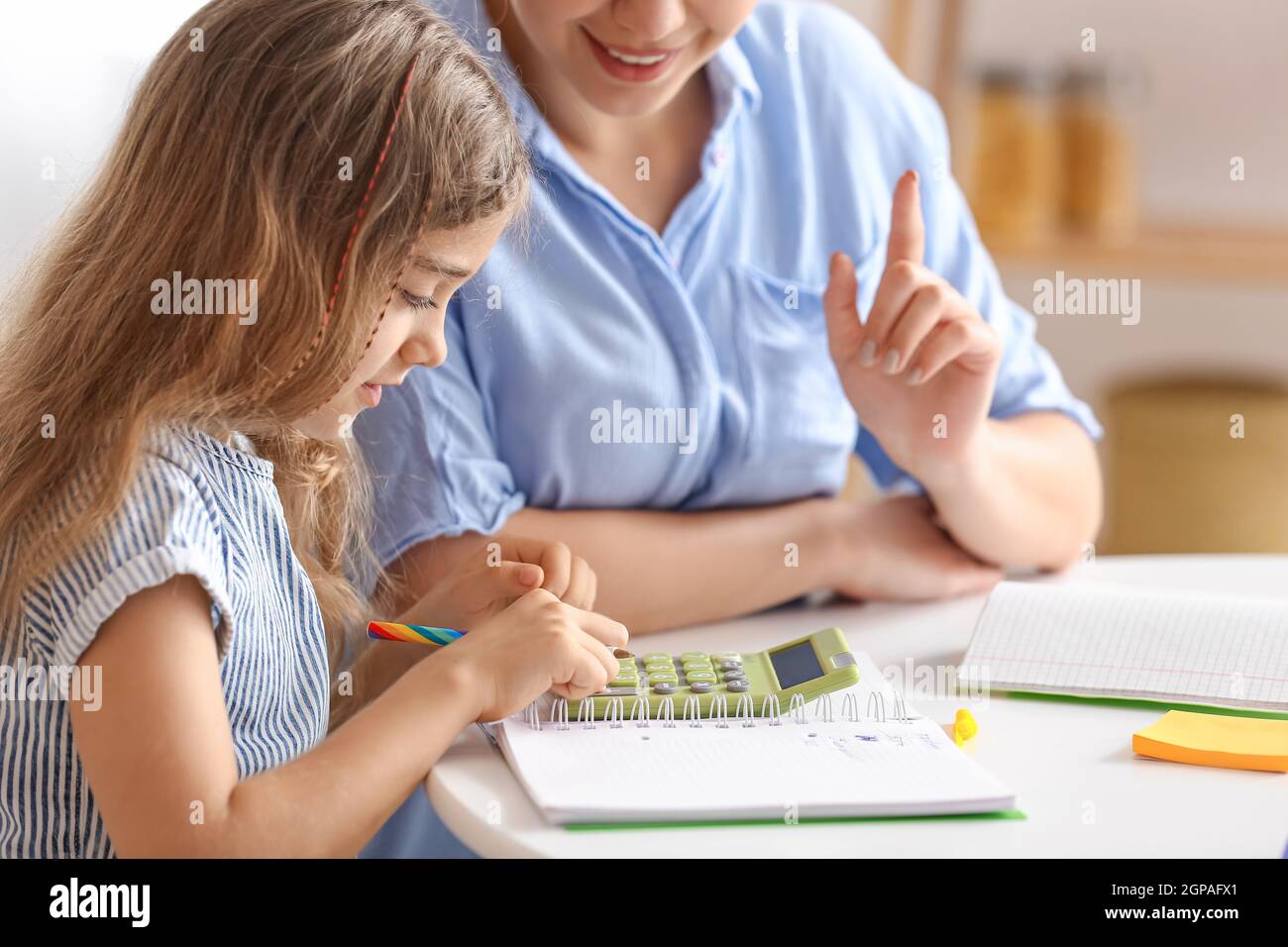 Little girl with her mother doing lessons at home Stock Photo - Alamy