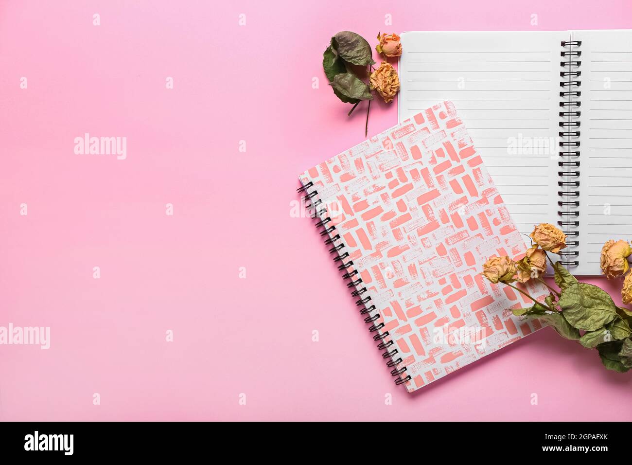 Notebooks and flowers on color background Stock Photo - Alamy