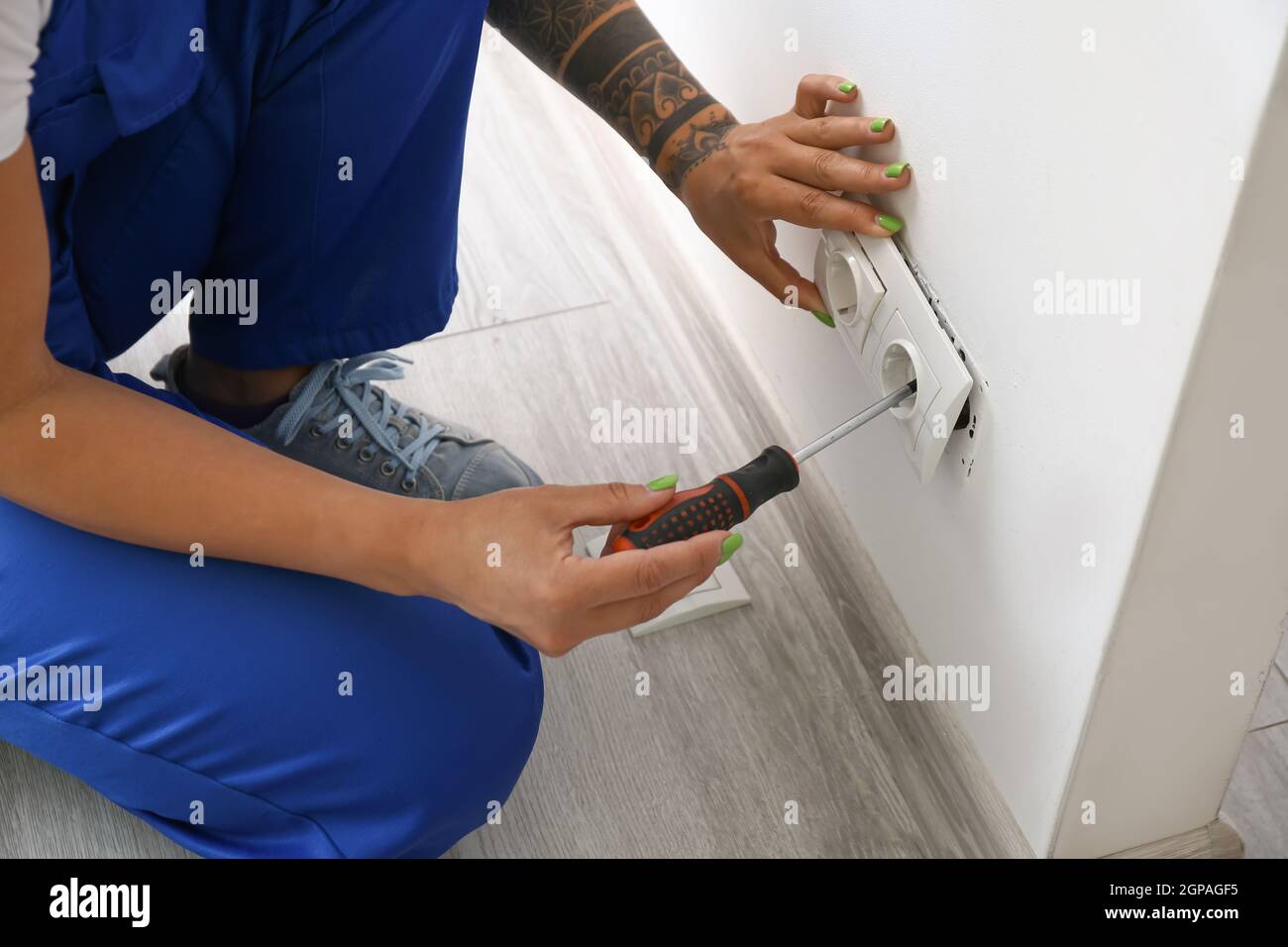 Female electrician repairing socket in room Stock Photo - Alamy