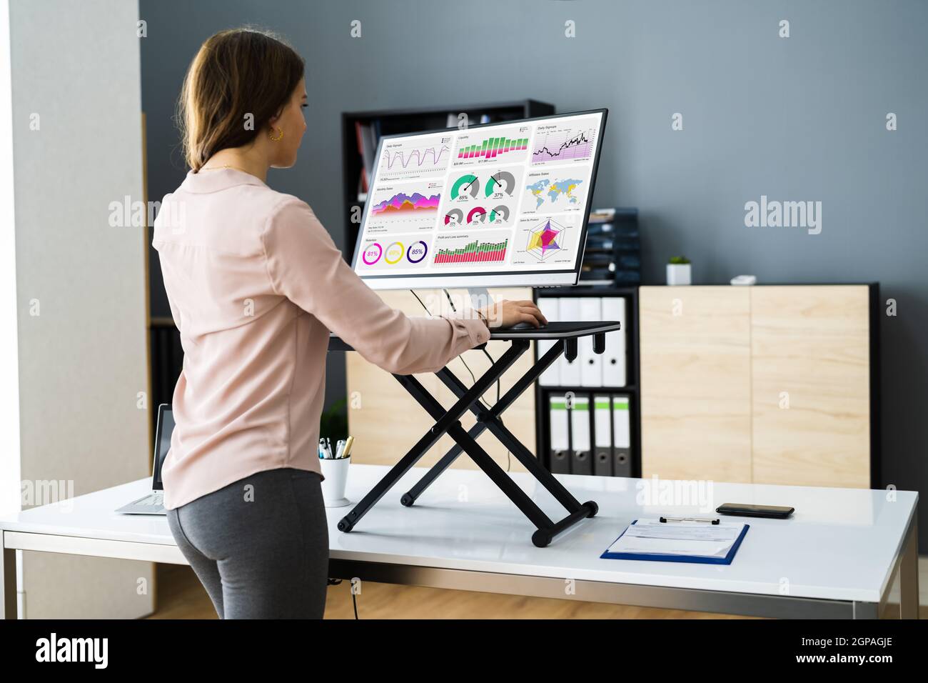 Adjustable Height Desk Stand In Office Using Computer Stock Photo - Alamy