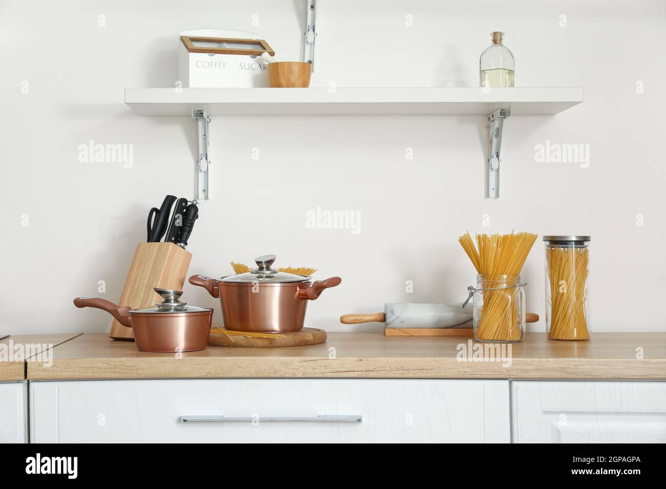 Copper cooking pots and jars with raw pasta on kitchen counter near ...
