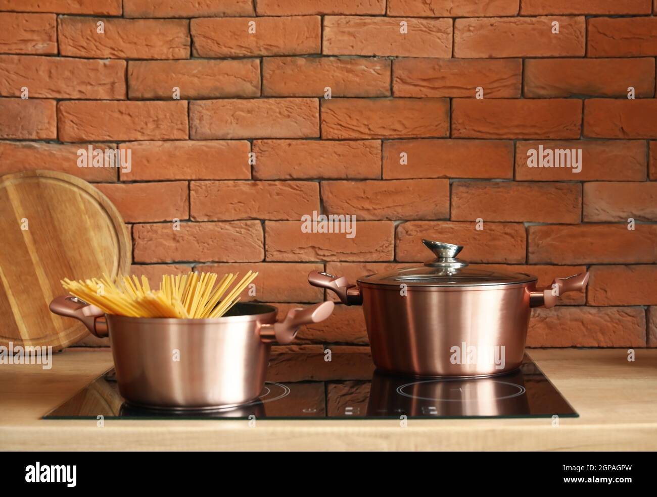 Copper cooking pots with raw spaghetti on stove in modern kitchen Stock ...