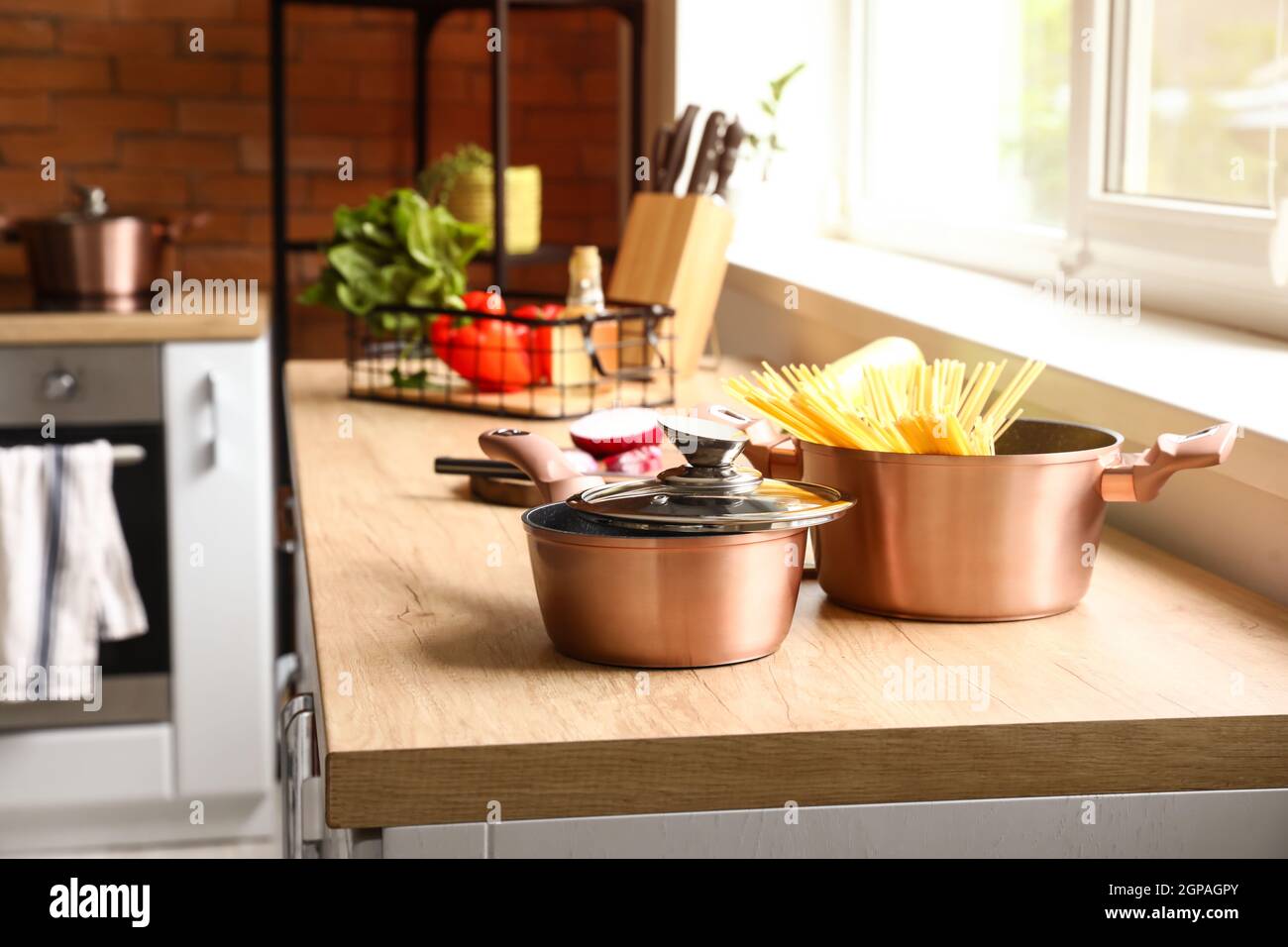 Copper cooking pots with raw pasta on counter in kitchen Stock Photo ...