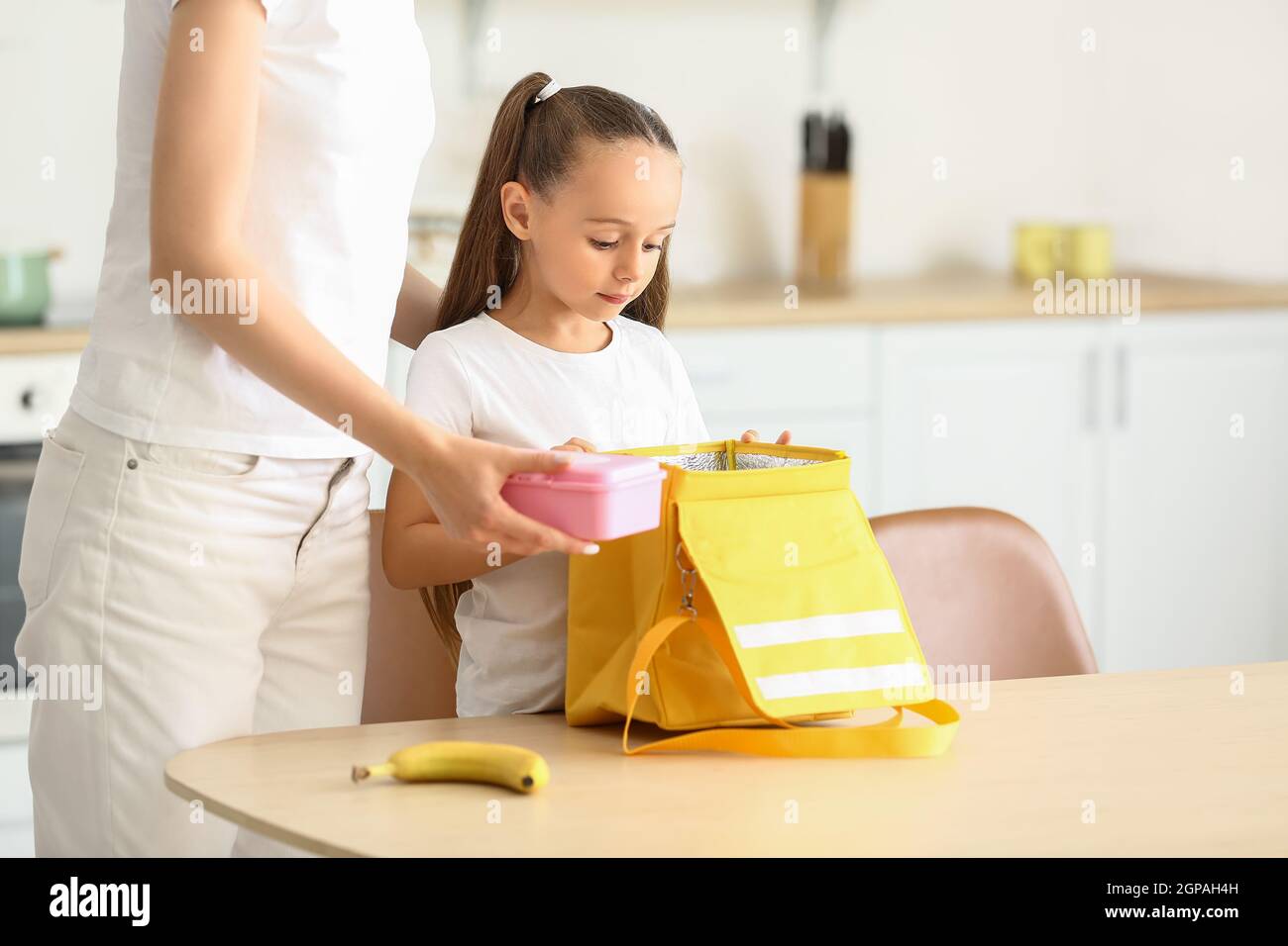 Mother packing school lunch for her little daughter at home Stock Photo ...