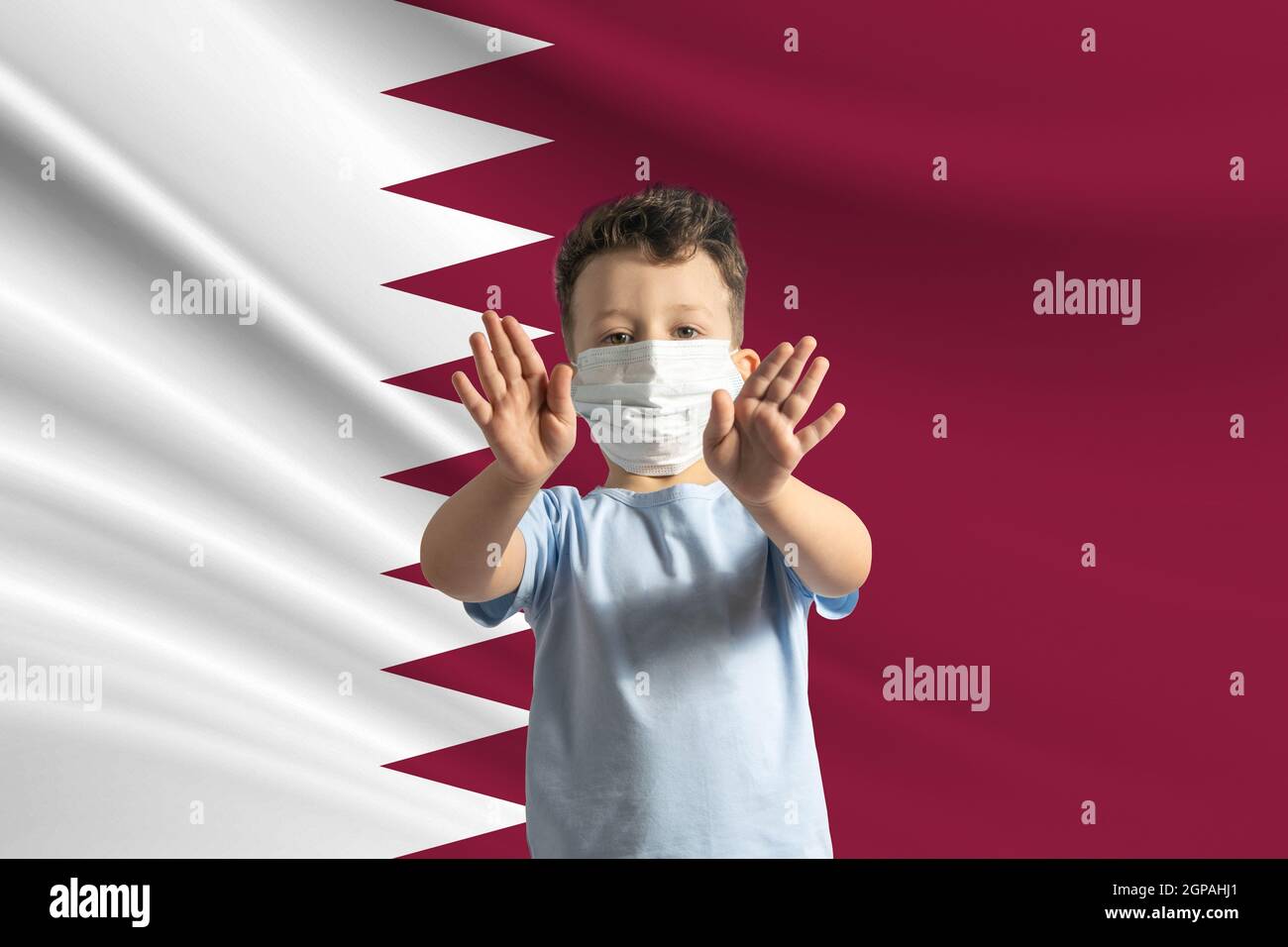 Little white boy in a protective mask on the background of the flag of ...