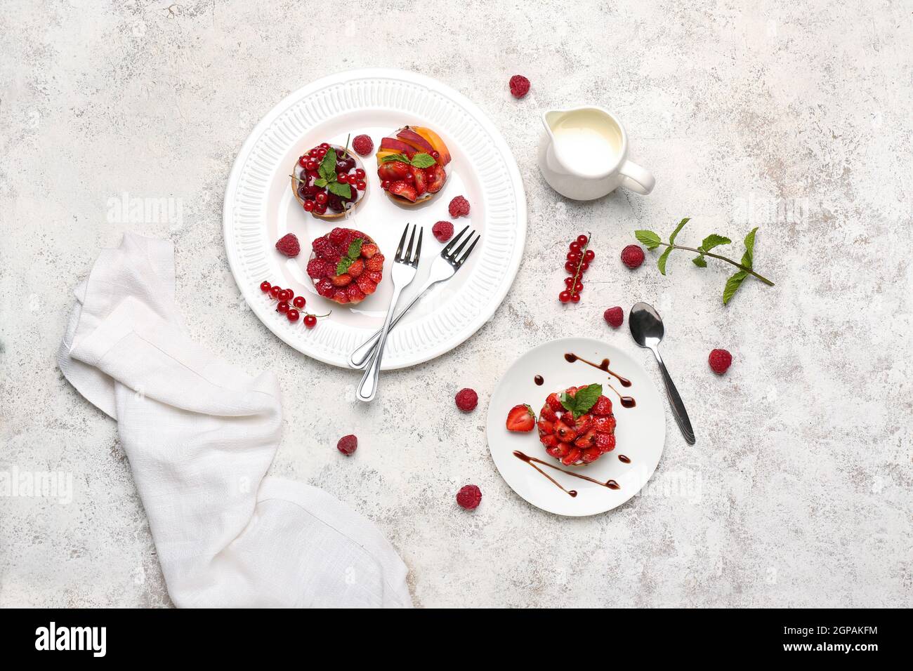 Plates with tasty berry tartlets on grunge background Stock Photo - Alamy