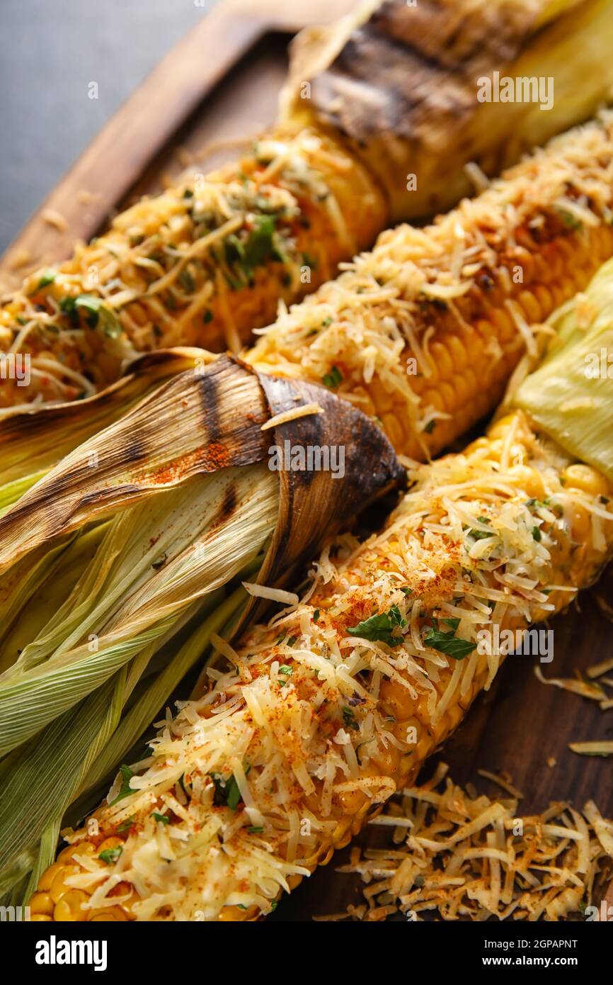 Wooden board with delicious Elote Mexican Street Corn on table, closeup ...