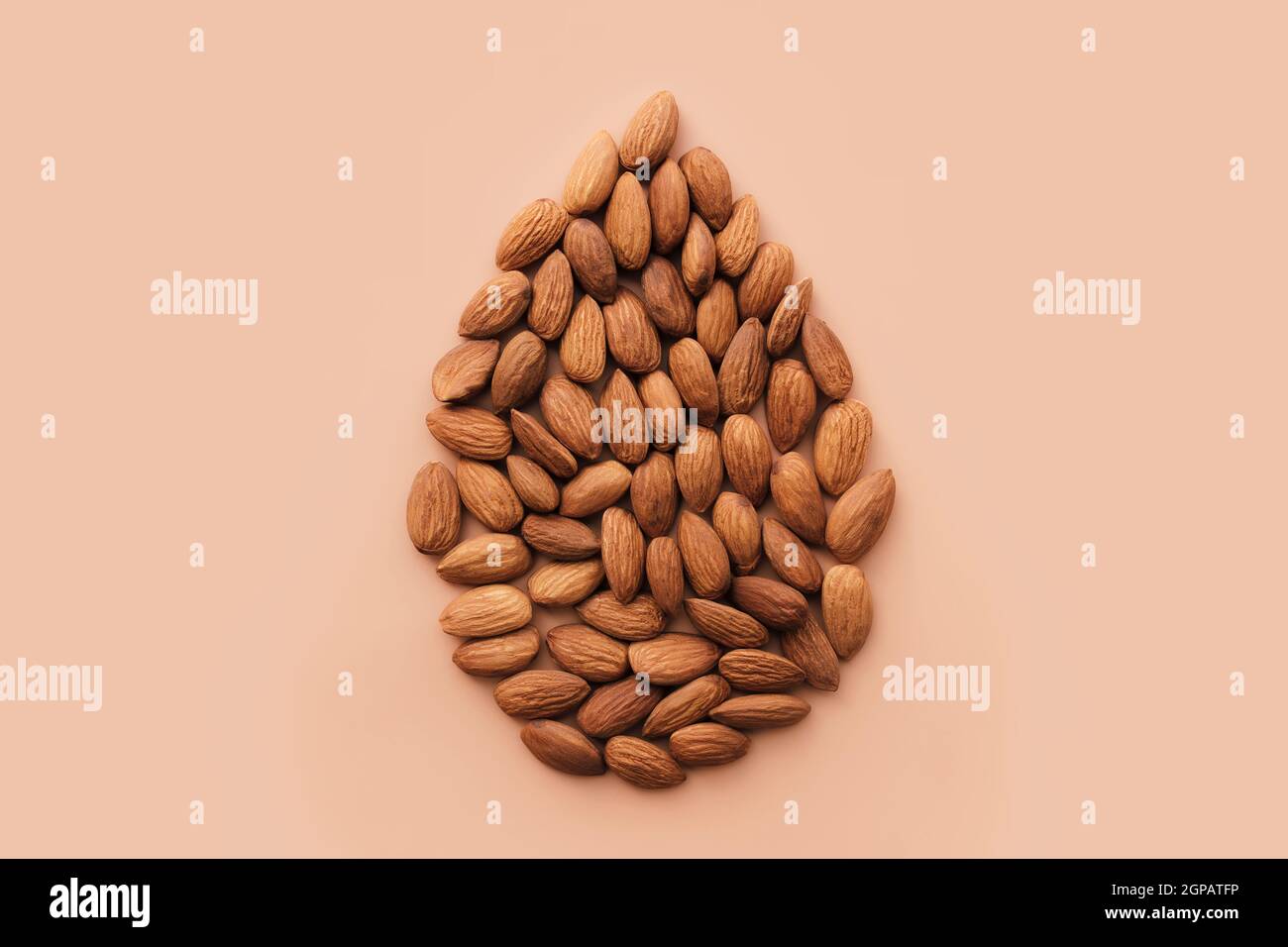 Raw almond kernels drop shape on beige background. Cosmetic and healthy ...