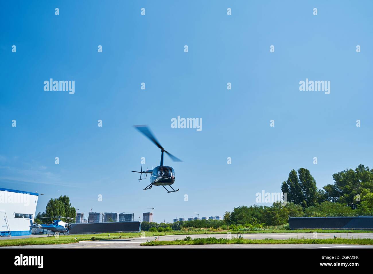 Manned helicopter overflying helipad on clear day Stock Photo - Alamy