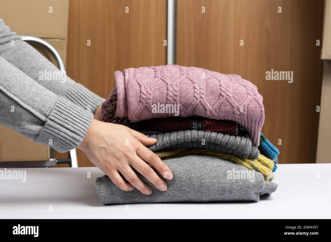 female hand holding a stack of clothes, help and volunteering concept ...