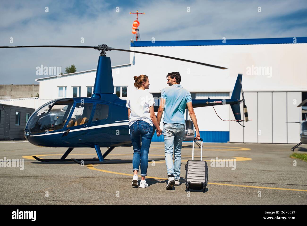 Romantic tourist couple approaching helicopter on helipad Stock Photo ...