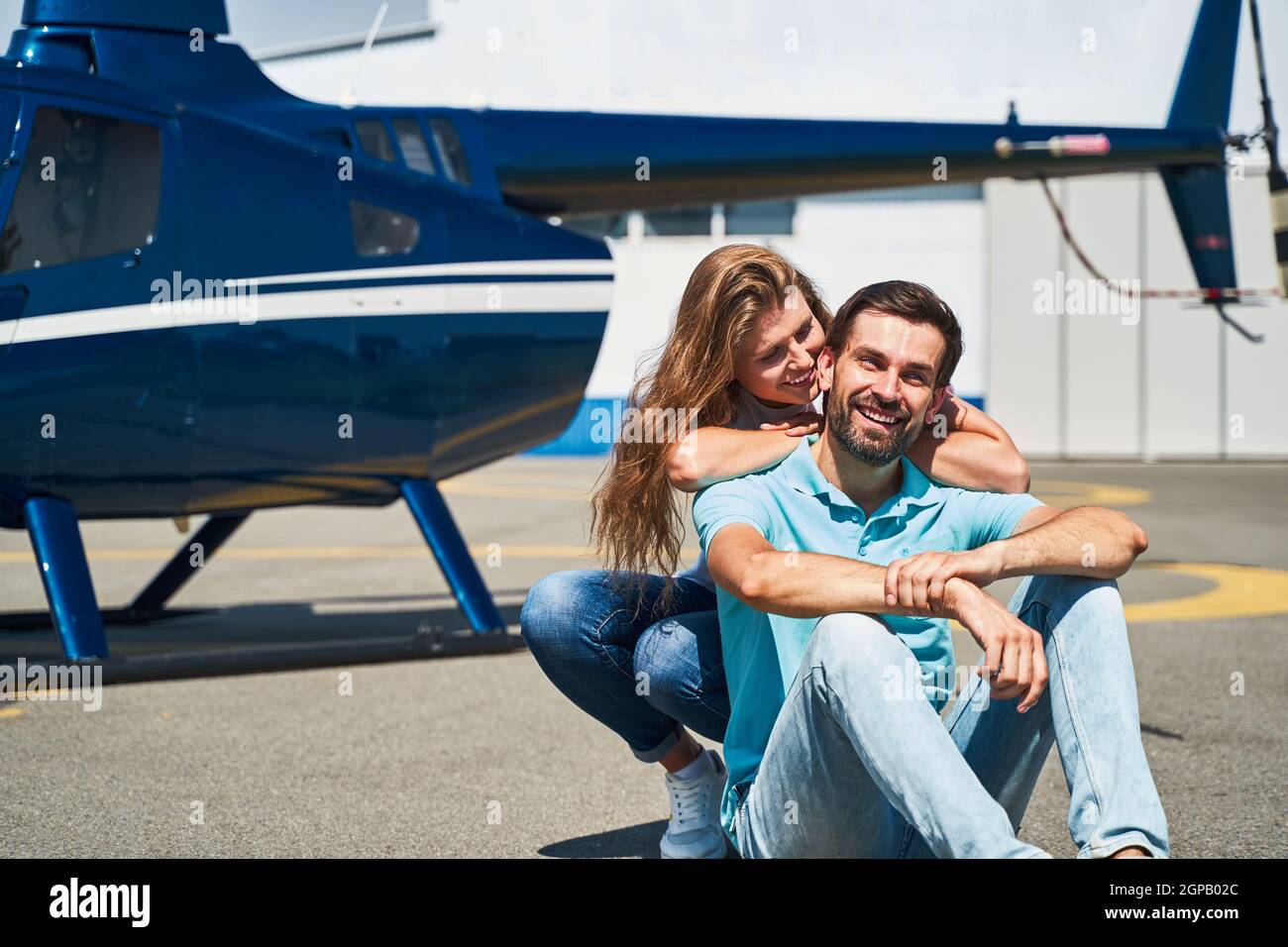 Romantic couple sitting on landing pad by helicopter Stock Photo - Alamy