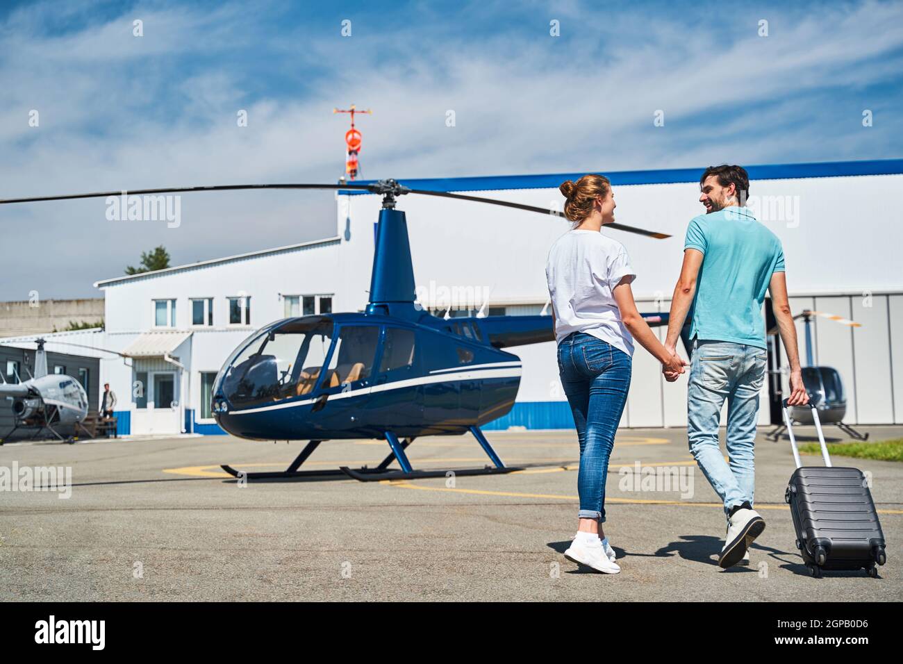 Romantic Caucasian couple with luggage approaching helicopter Stock ...