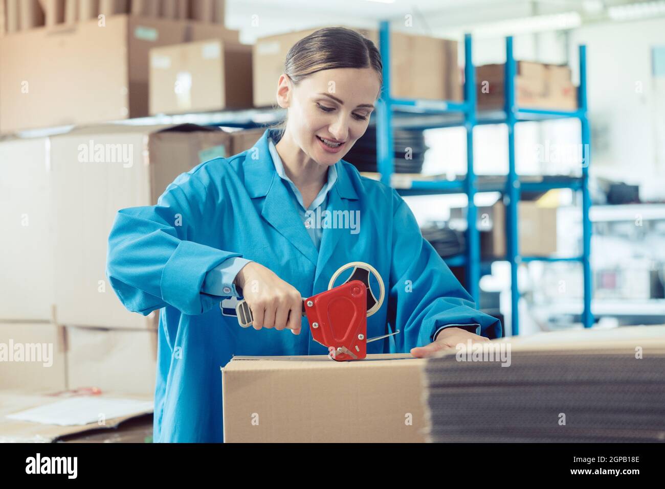 Woman in factory warehouse packaging goods for shipment in boxes Stock ...