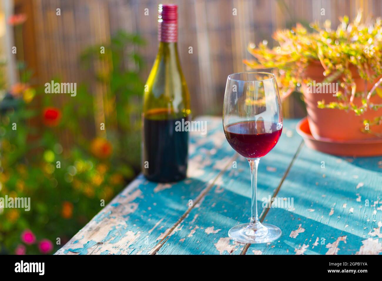 Glass of red wine on an old, rustic wood table. Enjoying it in the own ...