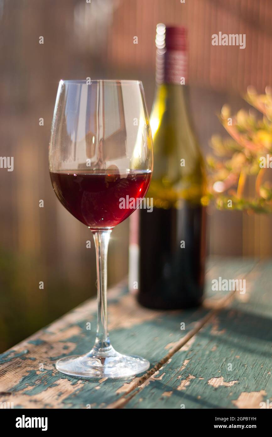 Glass of red wine on an old, rustic wood table. Enjoying it in the own ...