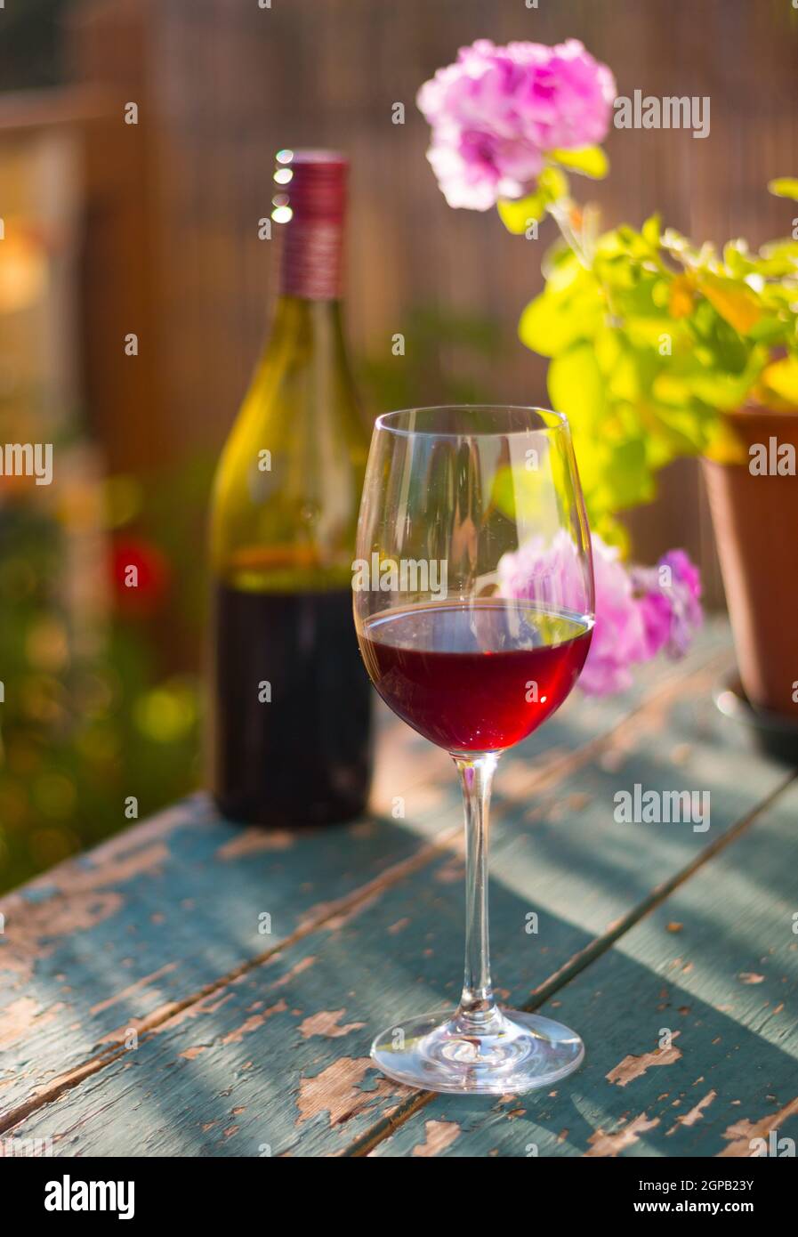 Glass of red wine on an old, rustic wood table. Enjoying it in the own ...