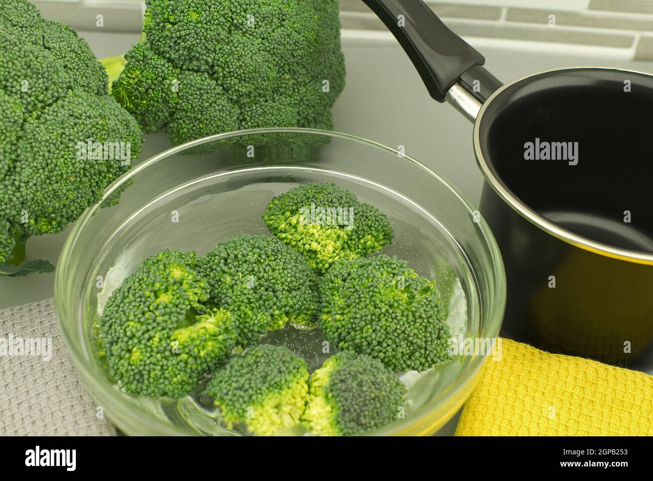 Fresh broccoli florets soaked in a clear bowl of water. Selective focus ...