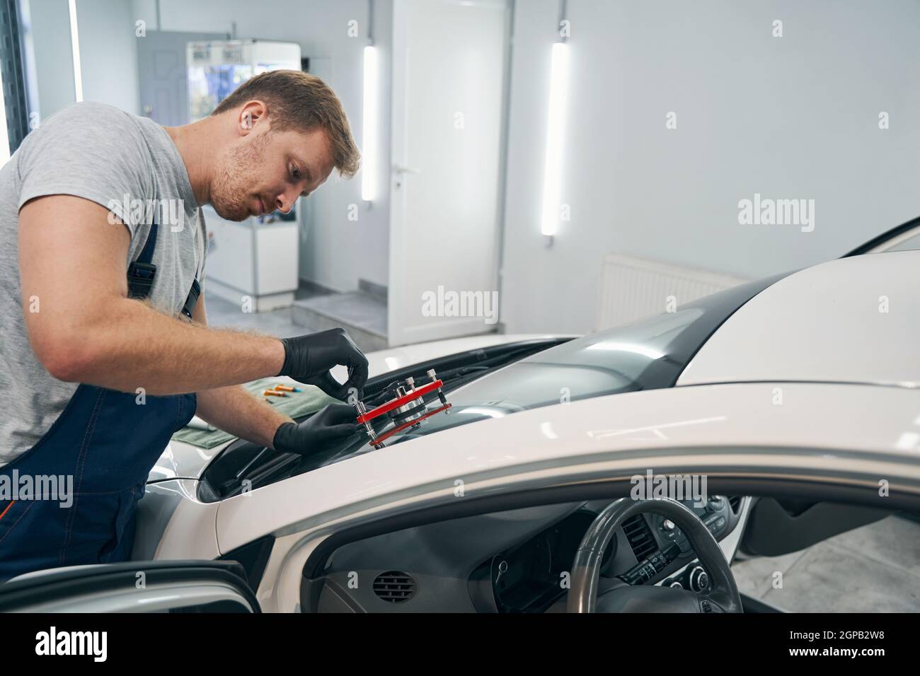 Closeup of man working with vacuum filler repair cracks in windshield ...