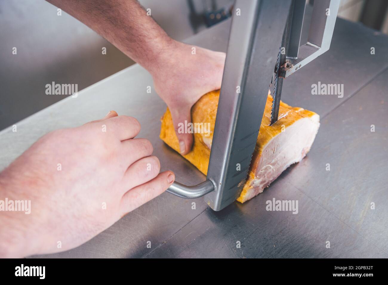 Butcher cutting meat in butchery with saw Stock Photo - Alamy