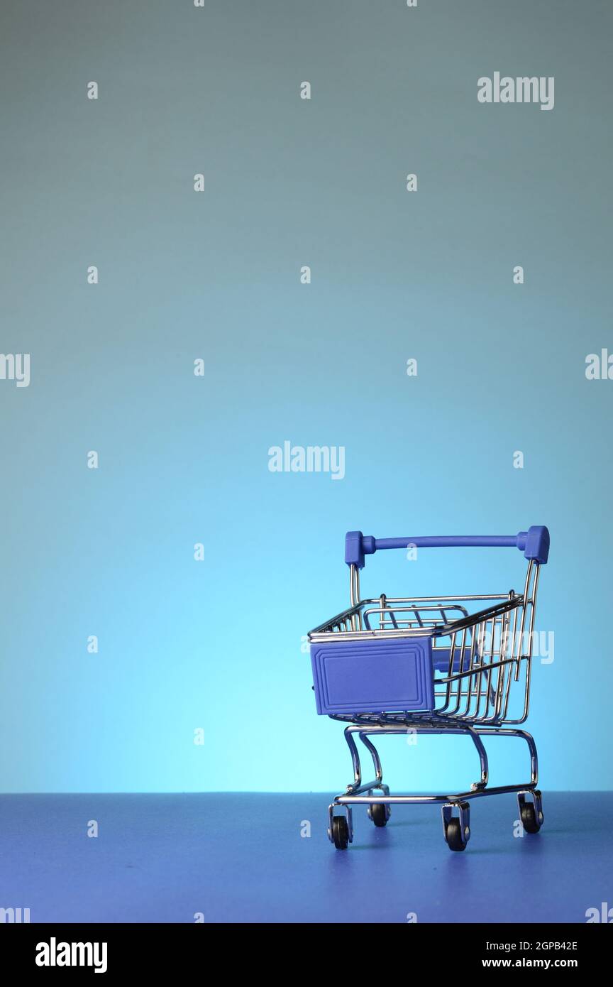A miniature blue shopping cart over a blue gradient background Stock ...