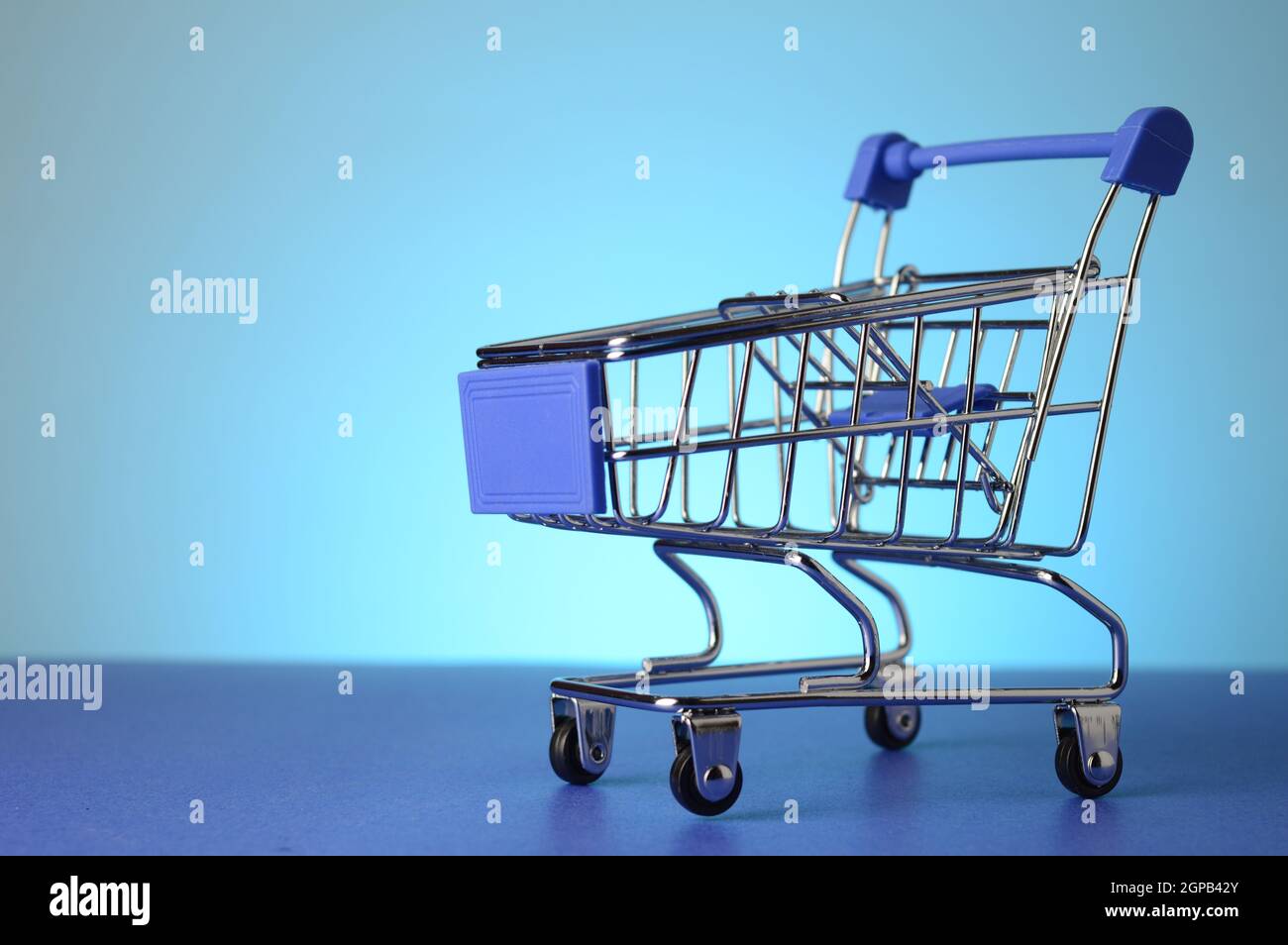 A miniature blue shopping cart over a blue gradient background Stock ...