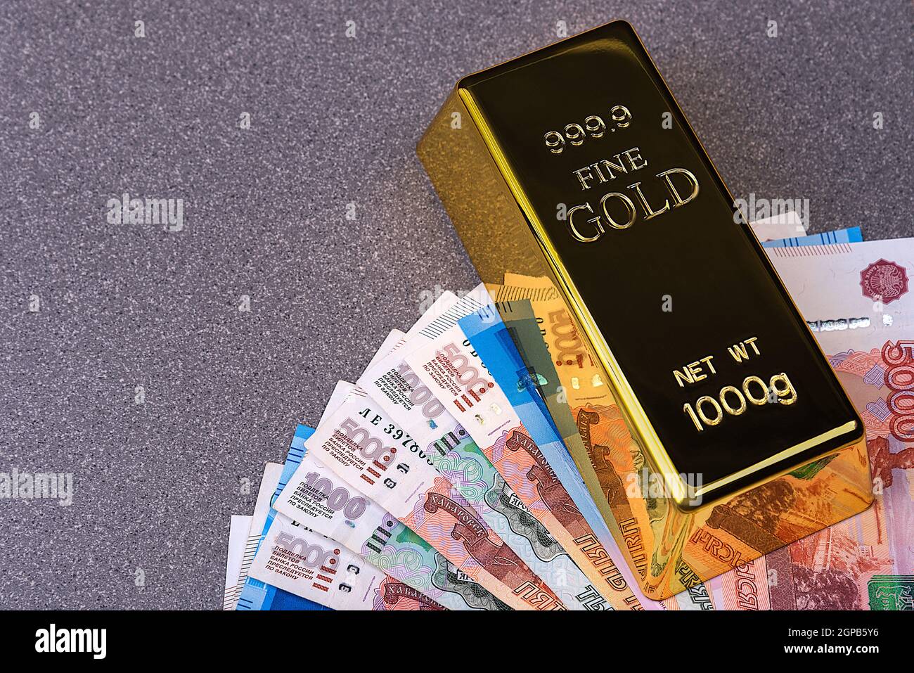 Gold bullion ingot and Russian ruble banknotes. The banknotes are ...