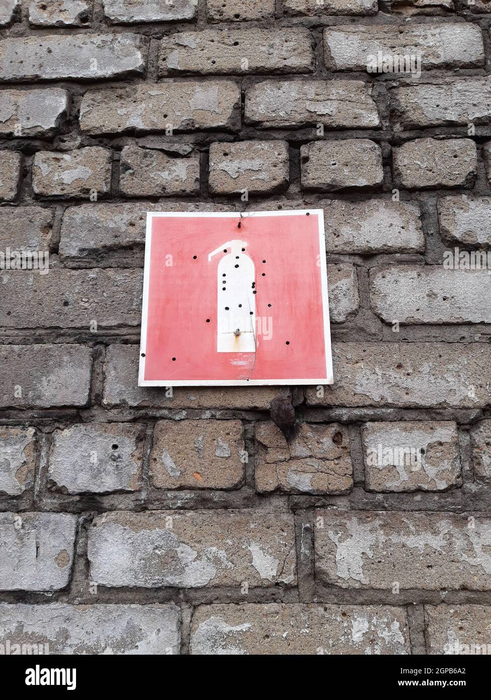 Fire extinguisher sign on brick wall with bullet holes Stock Photo - Alamy