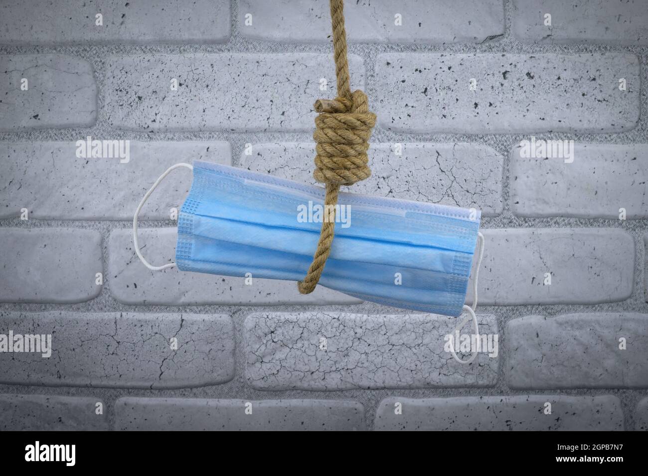 Rope noose around a protective surgical face mask, conceptual of death ...