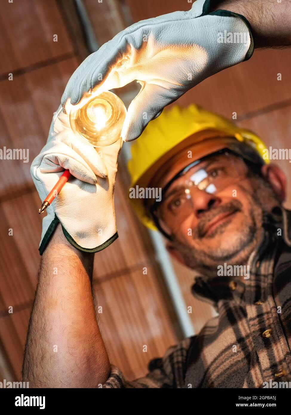 Electrician worker at work replaces the light bulb in a residential ...