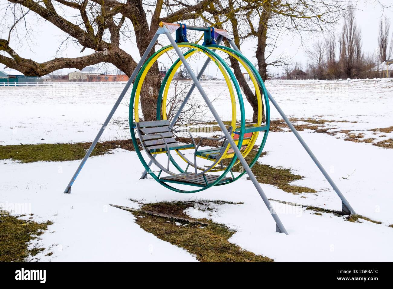 Children's playground in winter under snow. Swing, carousel and slide ...