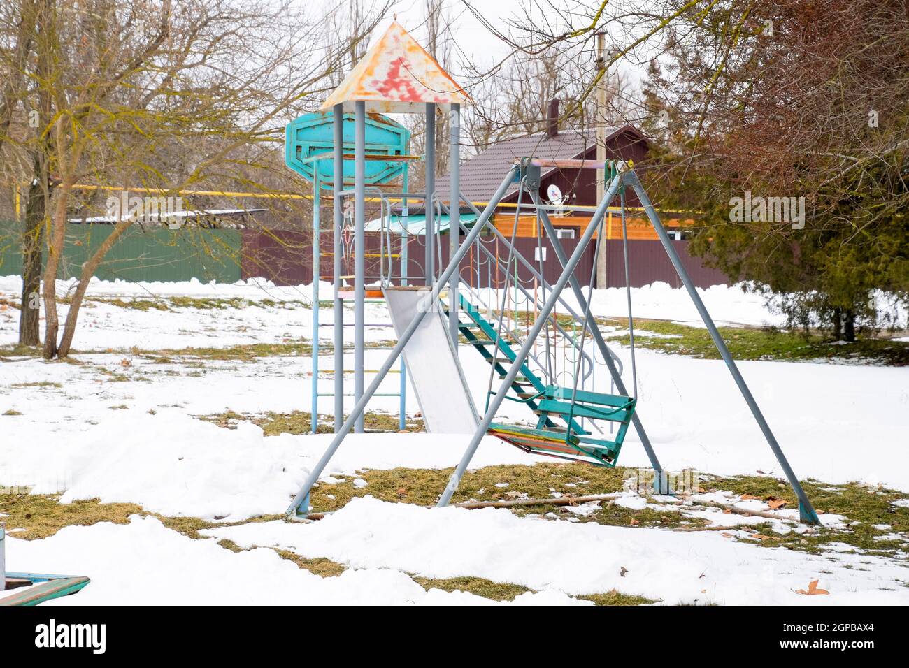 Children's playground in winter under snow. Swing, carousel and slide ...